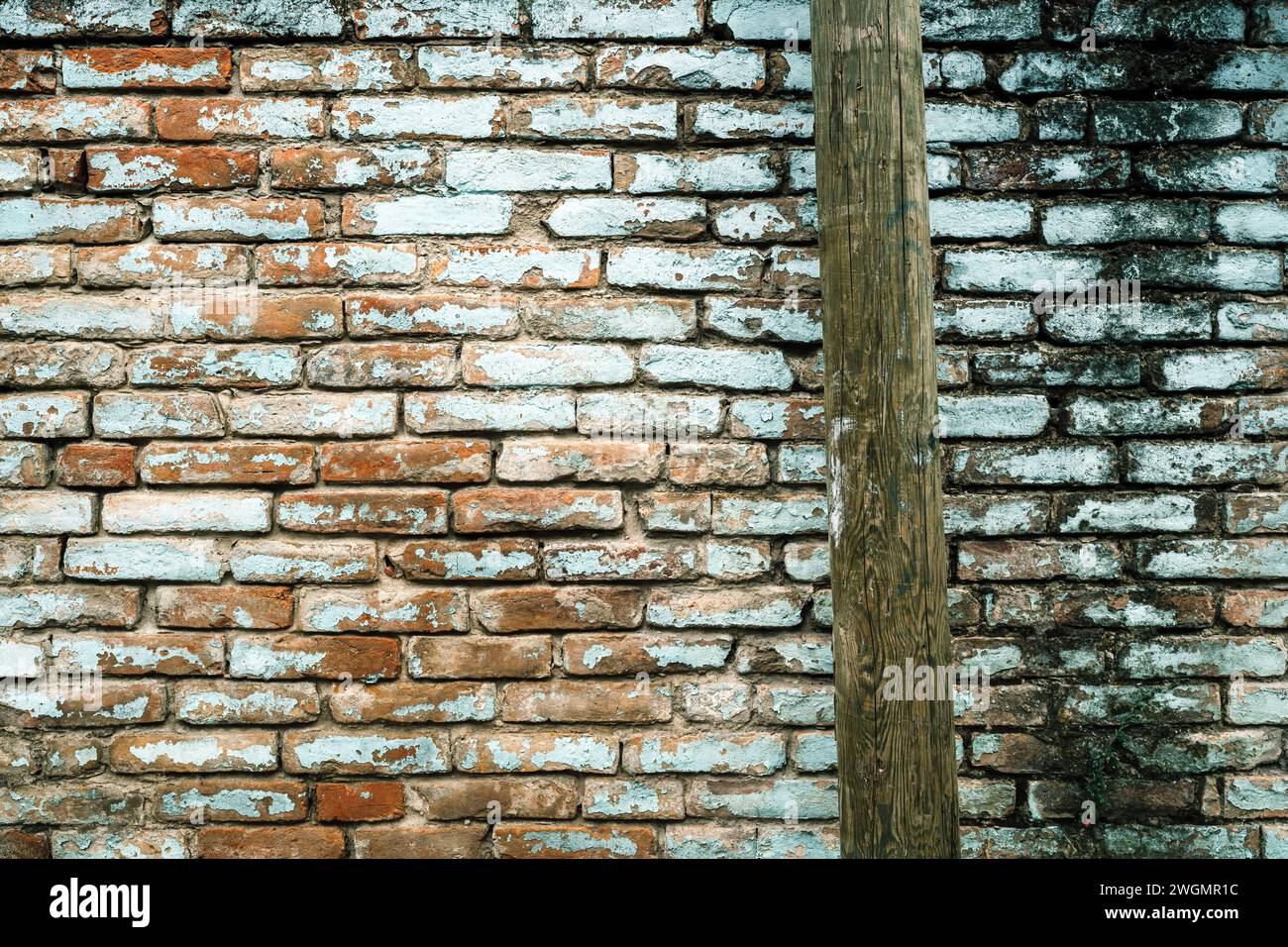 Wooden post in front of worn brick wall surface, urban street ...