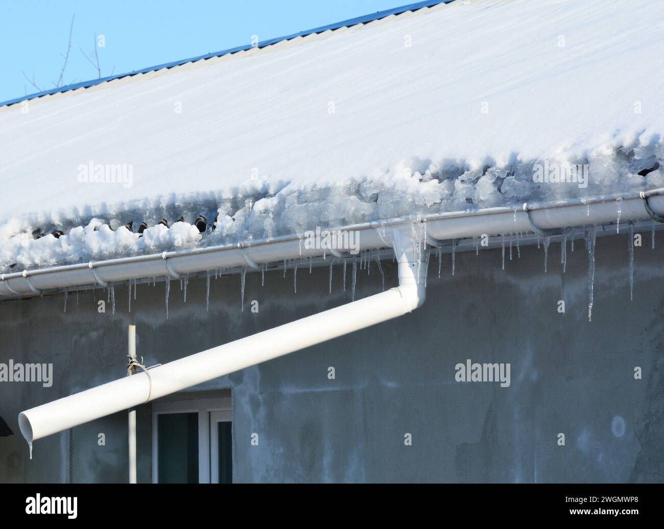 Frozen gutters damage. House roof covered snow, icicles and frozen roof ...