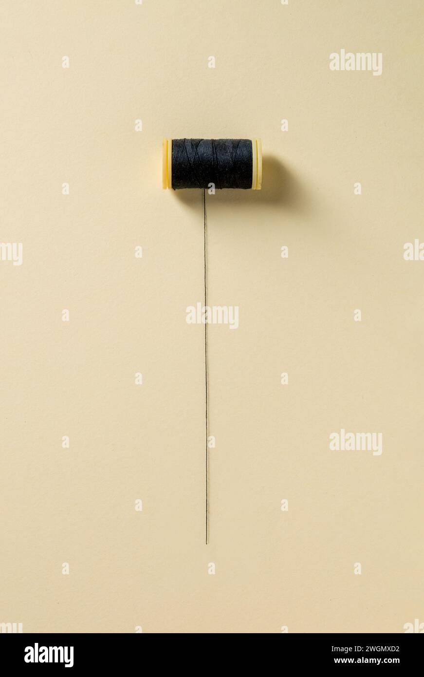 Black sewing thread wrapped around a partially unwrapped plastic spool ...