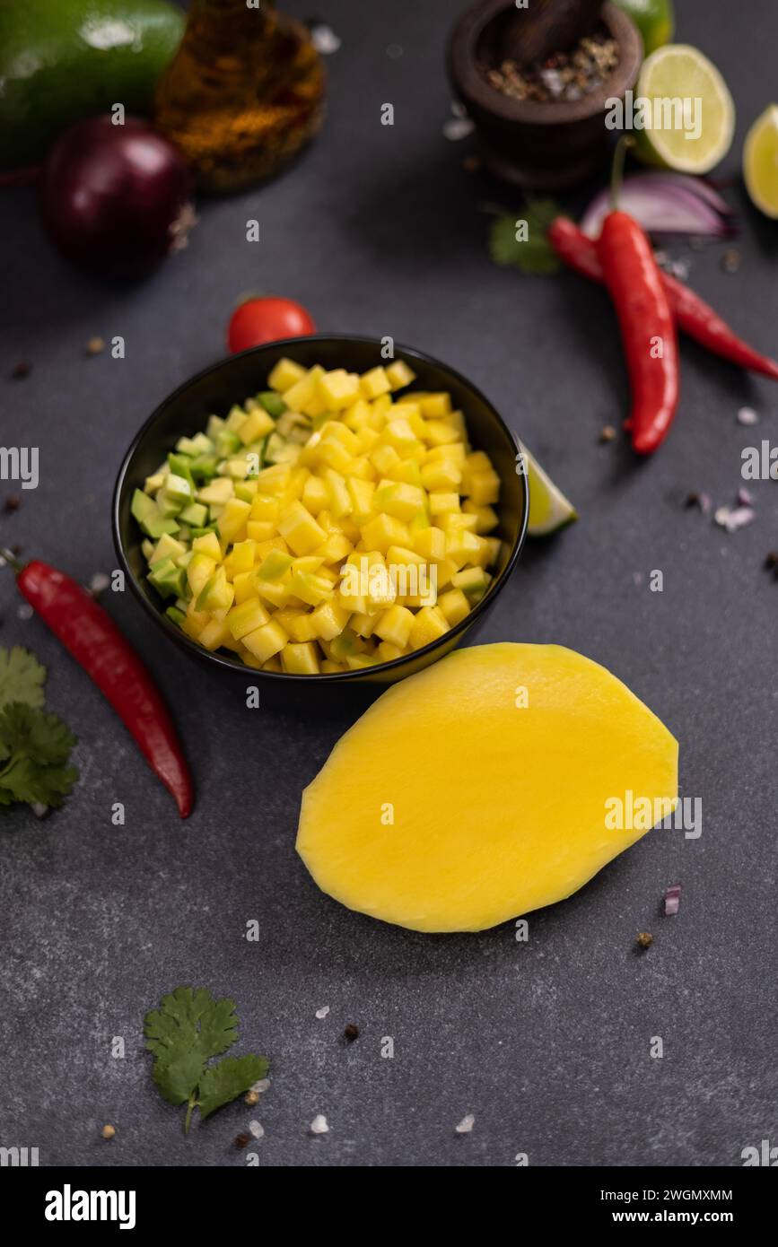 Cooking mango salsa - sliced chopped ingredients in a black ceramic ...