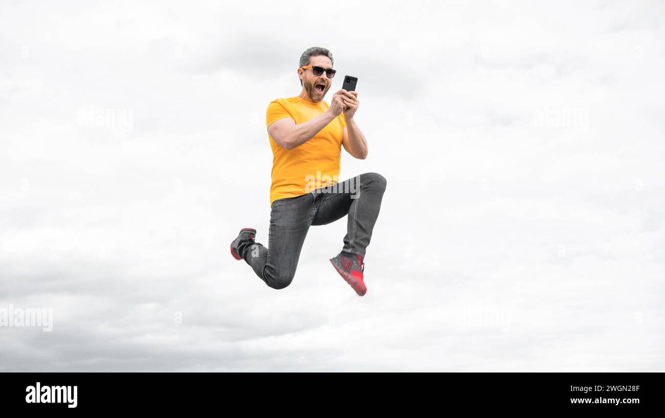 man jumping and chatting on phone on sky background Stock Photo - Alamy