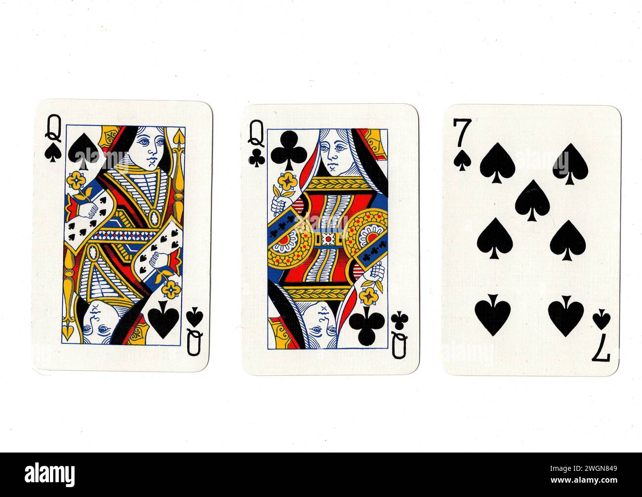 Vintage playing cards showing a pair of black queens and a black seven isolated on a white ...