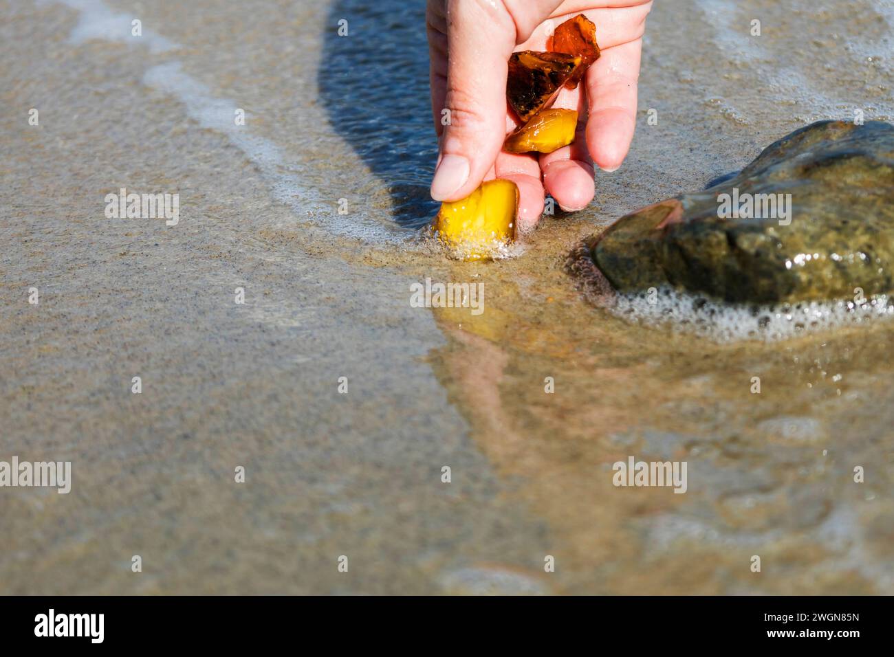 Beautiful pieces of amber in the hand of the sea background. A glowing ...