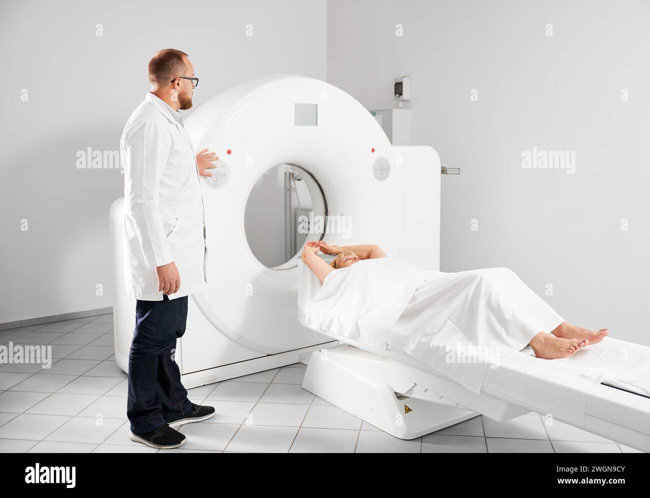 Medical computed tomography or MRI scanner. Male radiologist presses ...