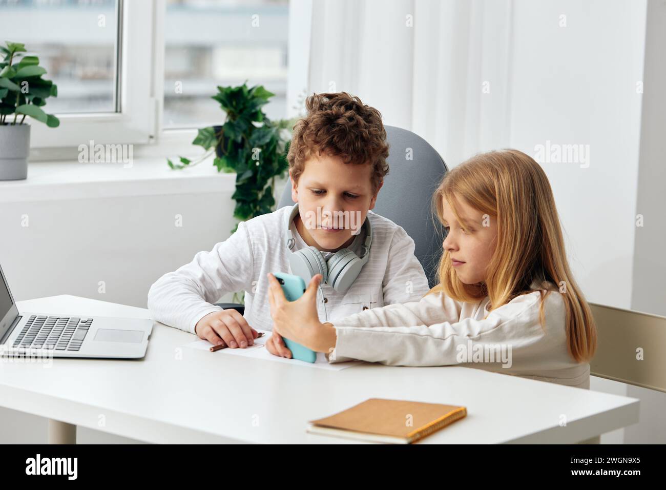 Happy brother and sister studying at home with their laptops and ...
