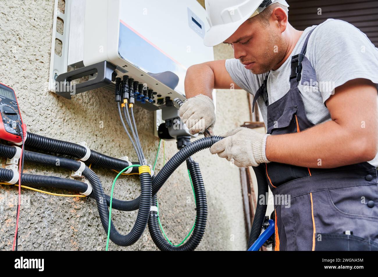 Man electrician installing solar panel system. Technician in helmet and ...