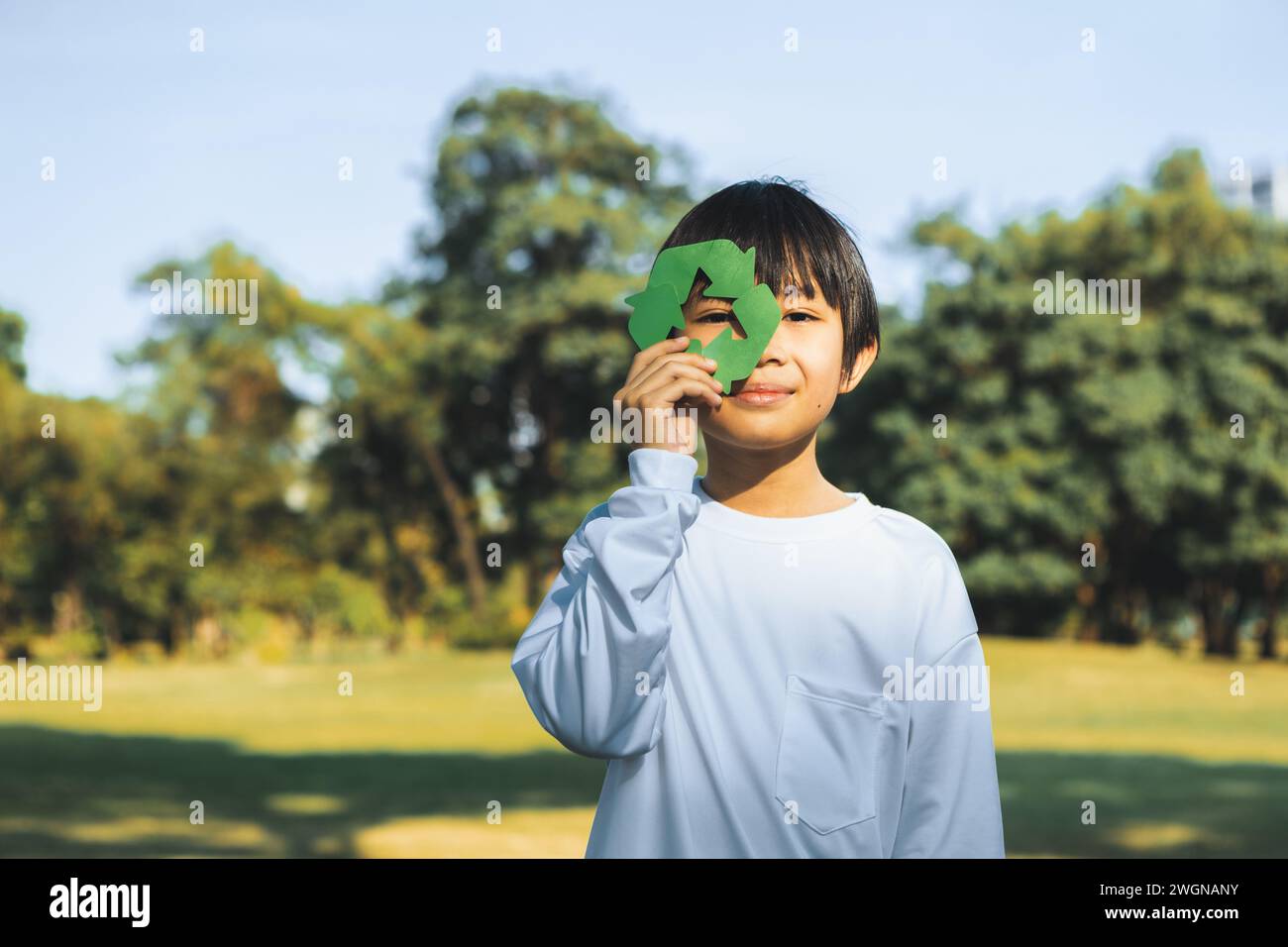 Cheerful young asian boy holding recycle symbol on daylight natural ...