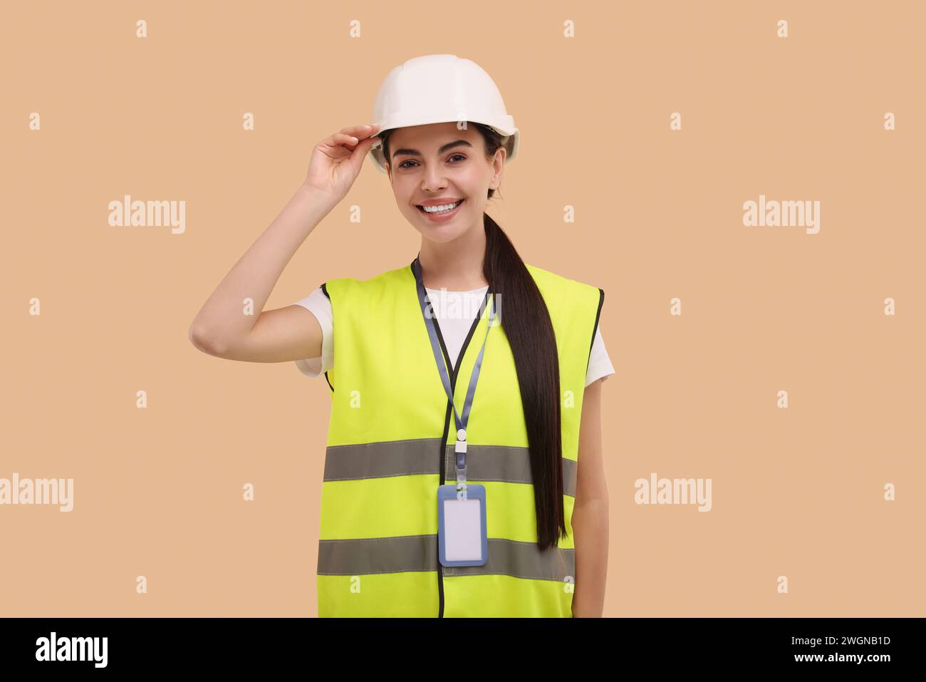 Engineer with hard hat and badge on beige background Stock Photo - Alamy
