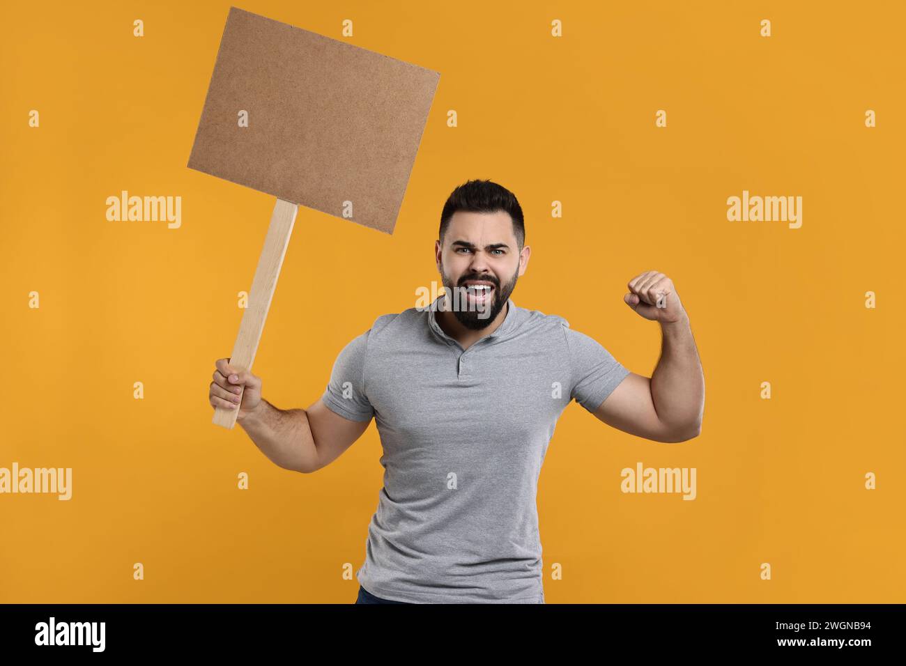 Angry man holding blank sign on orange background, space for text Stock ...