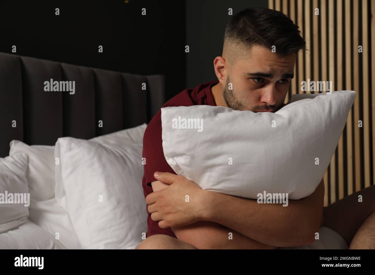 Sad man hugging pillow on bed at home. Space for text Stock Photo - Alamy