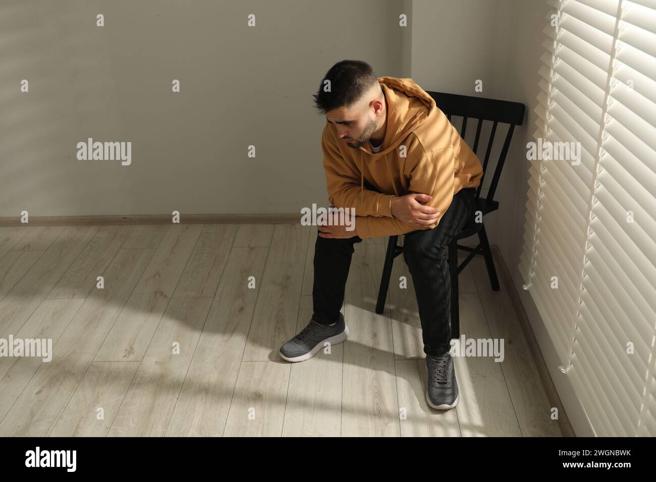 Sad man sitting on chair near window. Space for text Stock Photo - Alamy