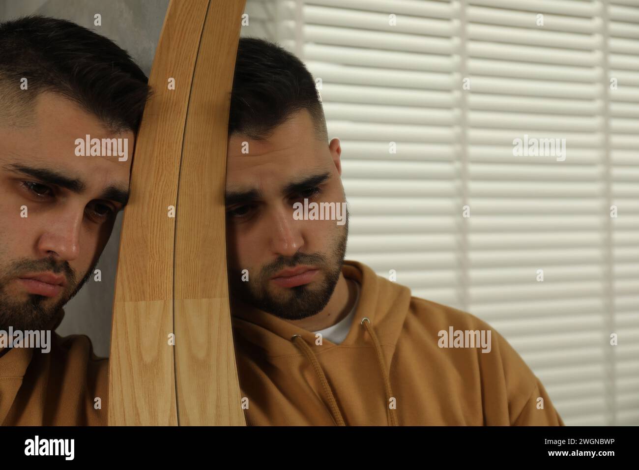 Sad young man near mirror at home Stock Photo - Alamy