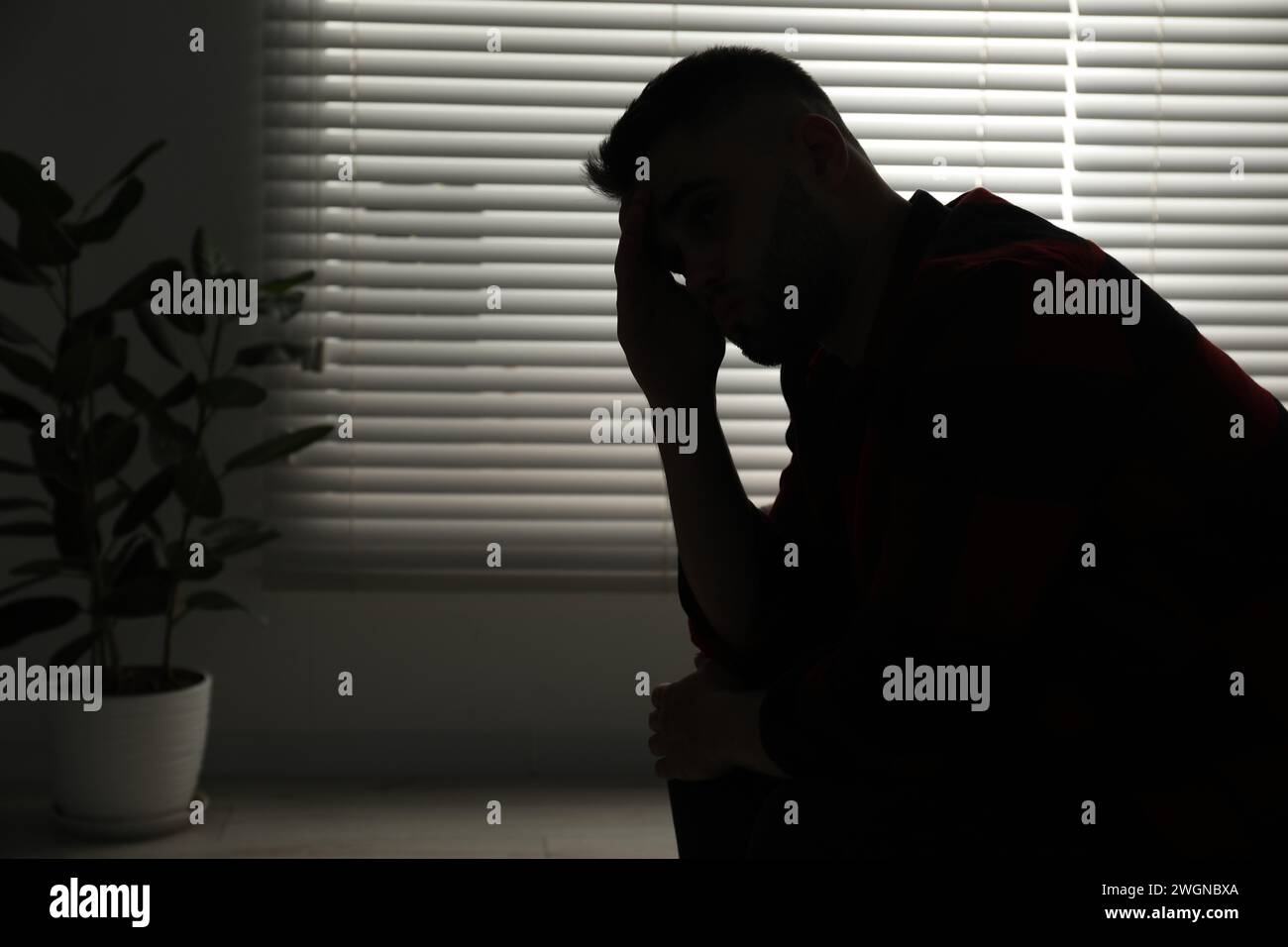 Silhouette of sad man near closed blinds indoors. Space for text Stock ...