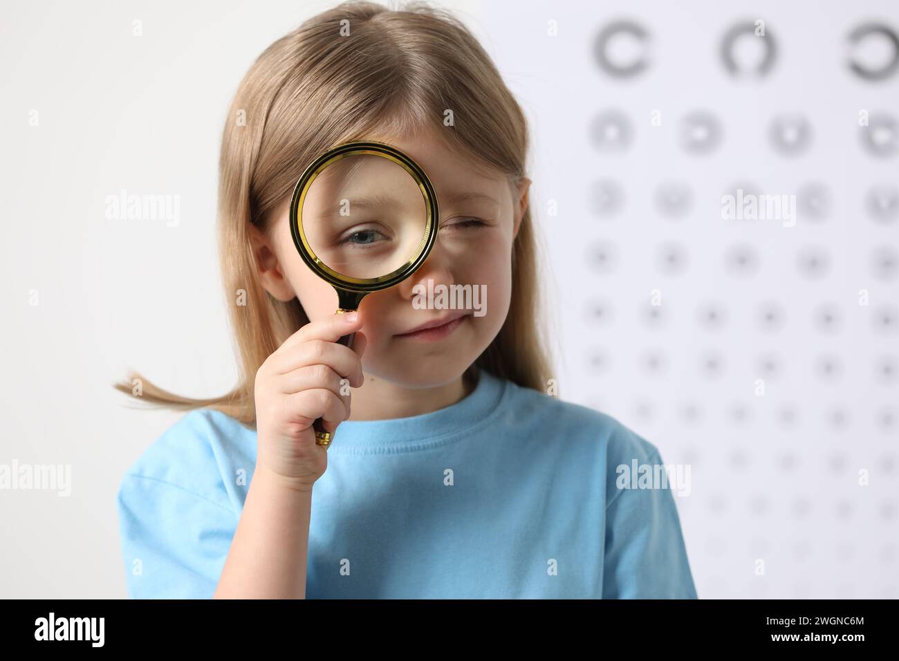 Little girl with magnifying glass against vision test chart Stock Photo ...