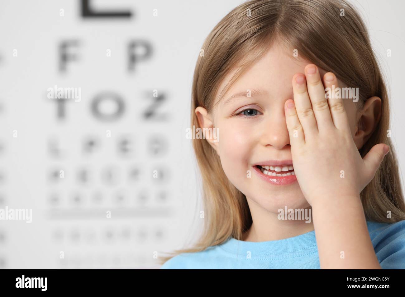 Little girl covering her eye against vision test chart Stock Photo - Alamy