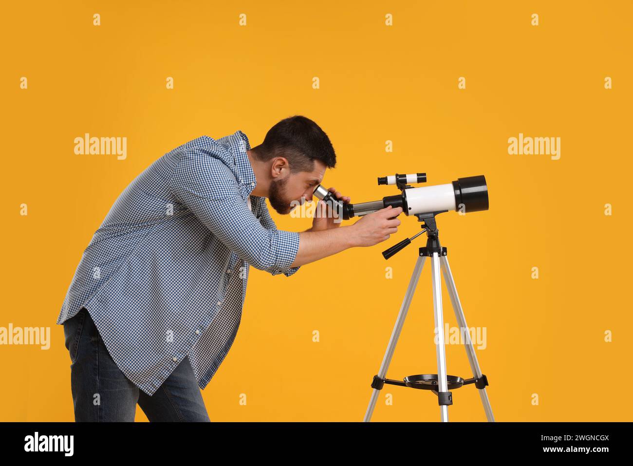 Astronomer looking at stars through telescope on orange background ...