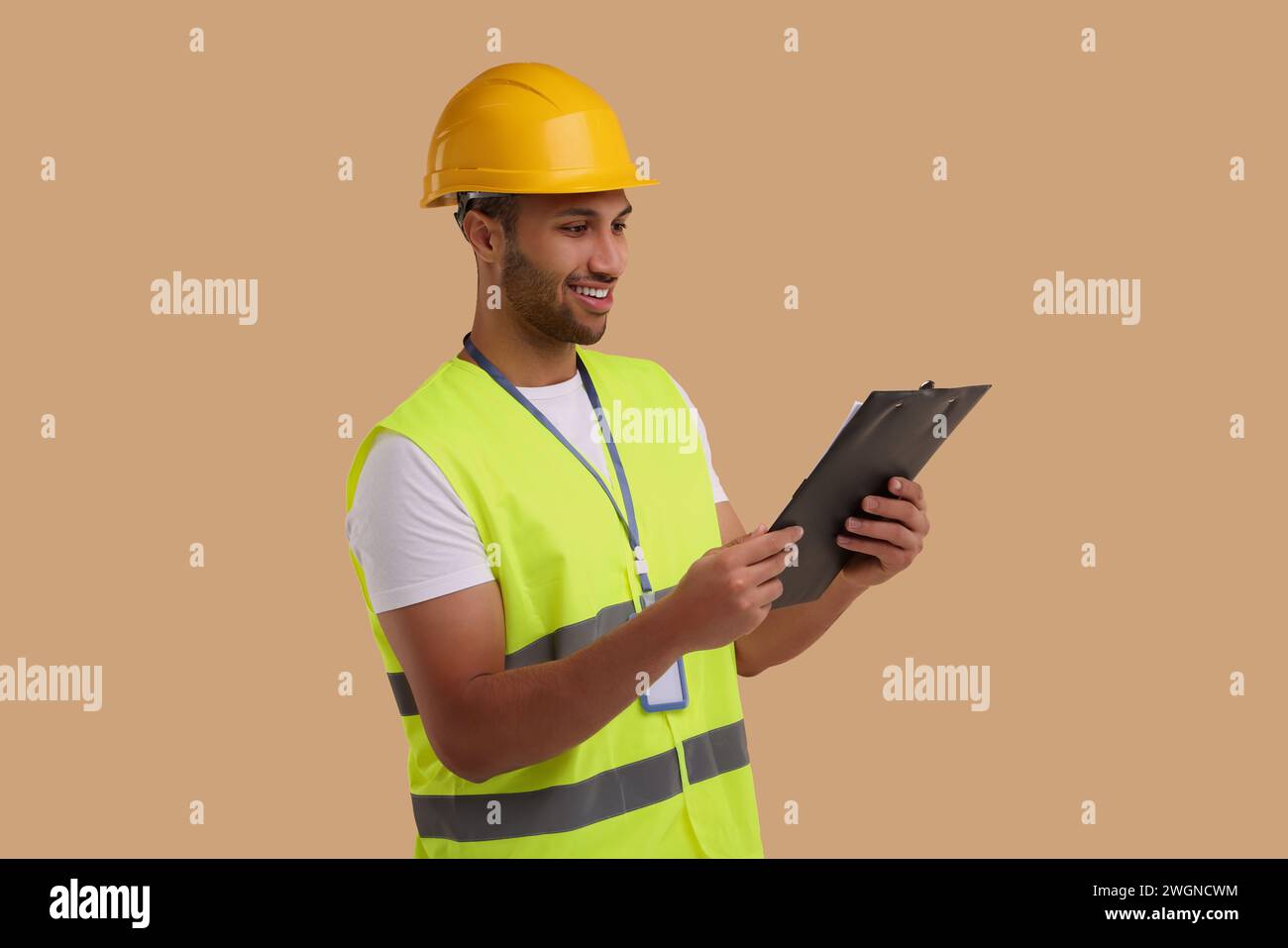 Engineer in hard hat holding clipboard on beige background Stock Photo ...