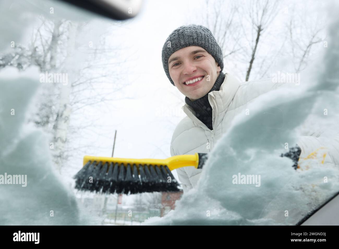 Man cleaning snow from car windshield, view from inside Stock Photo - Alamy
