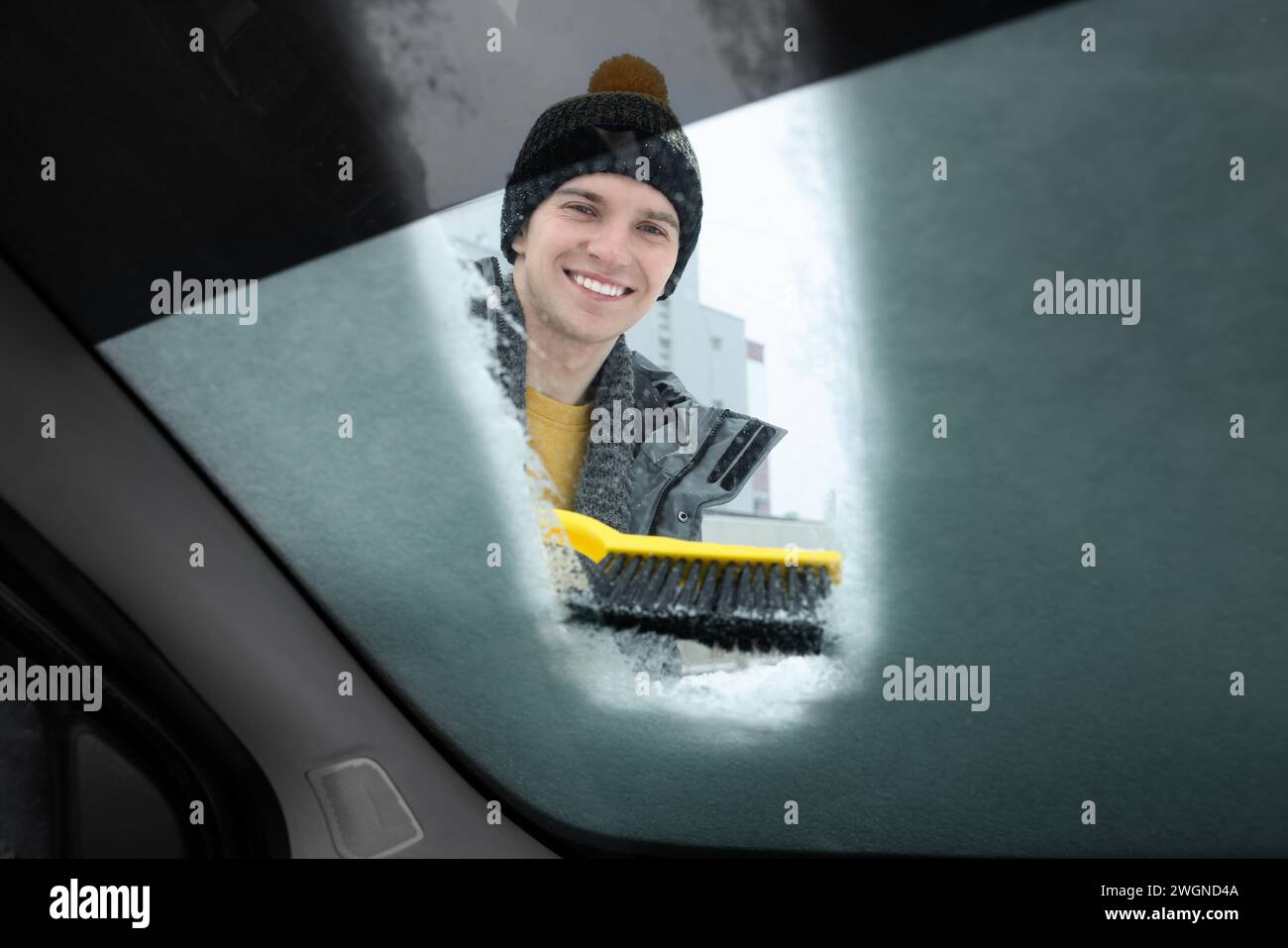 Man cleaning snow from car windshield, view from inside Stock Photo - Alamy