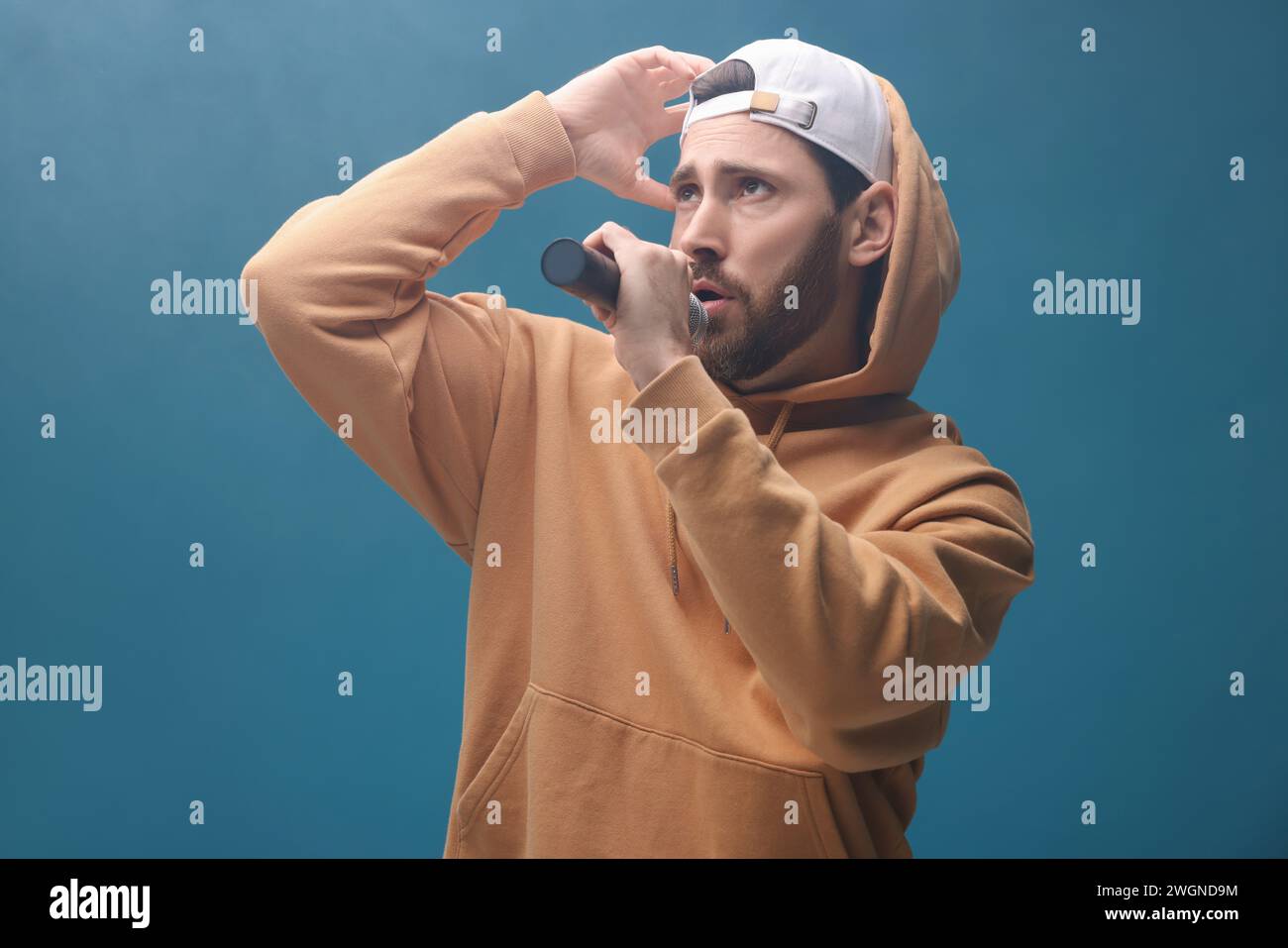 Singer with microphone rapping on light blue background Stock Photo - Alamy