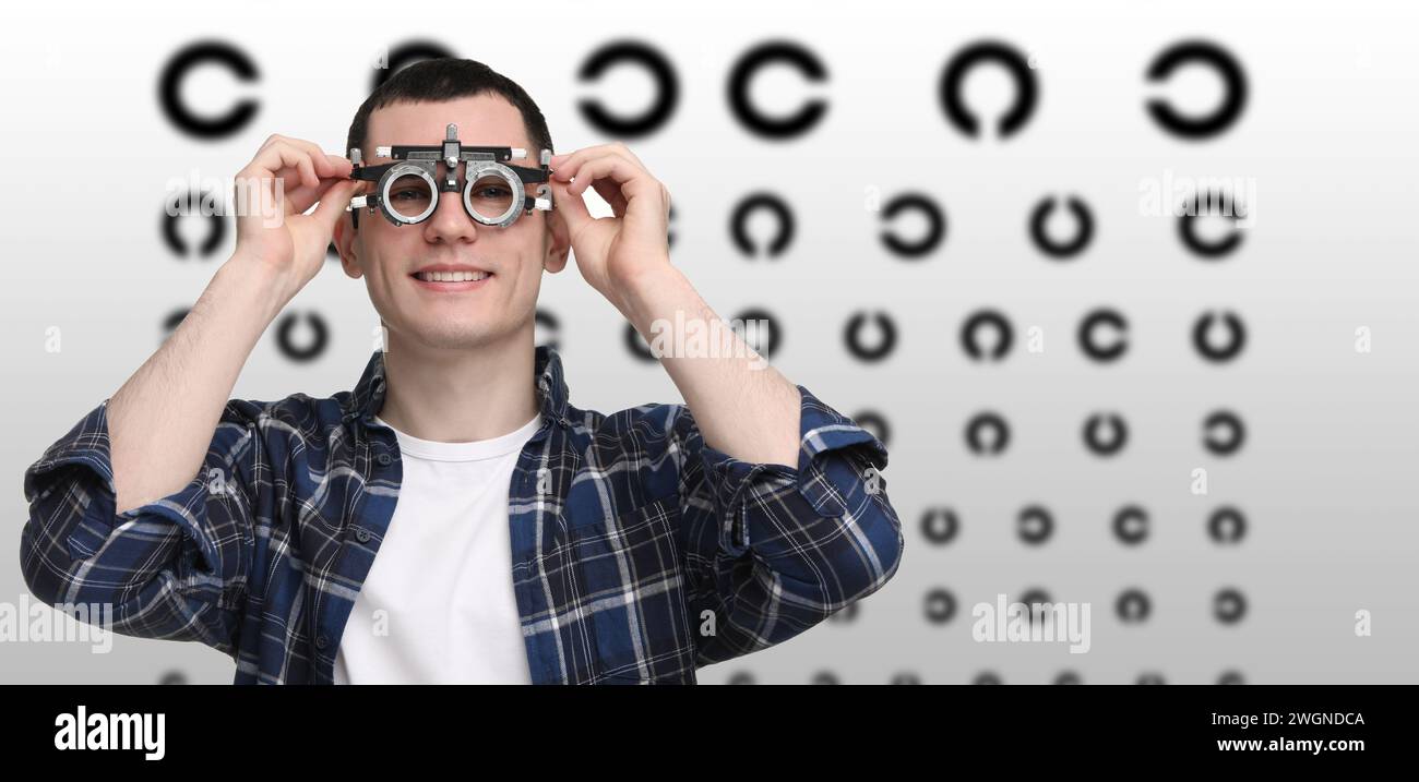 Vision test. Young man with trial frame and eye chart on gradient ...