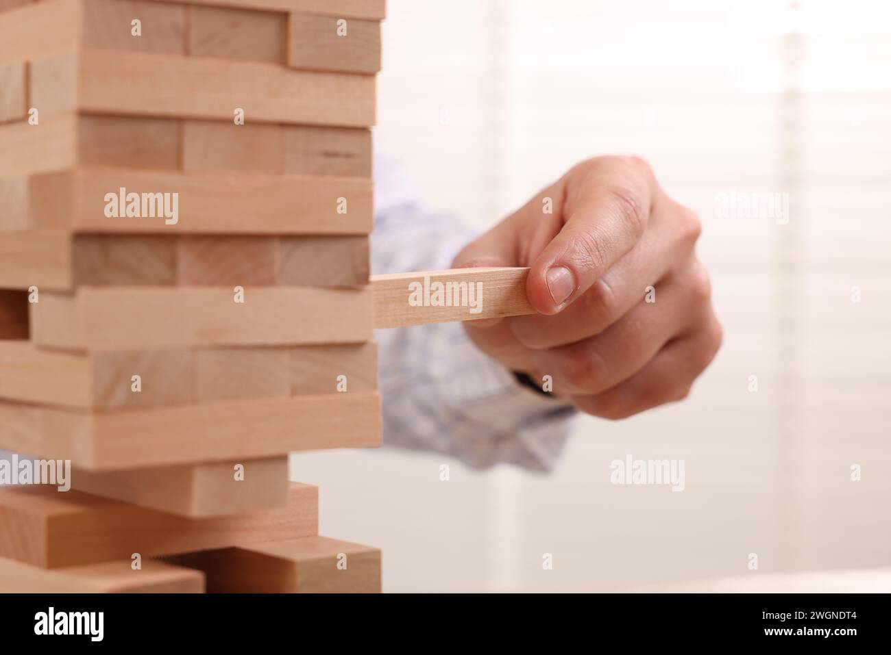 Playing Jenga. Man removing wooden block from tower indoors, closeup ...