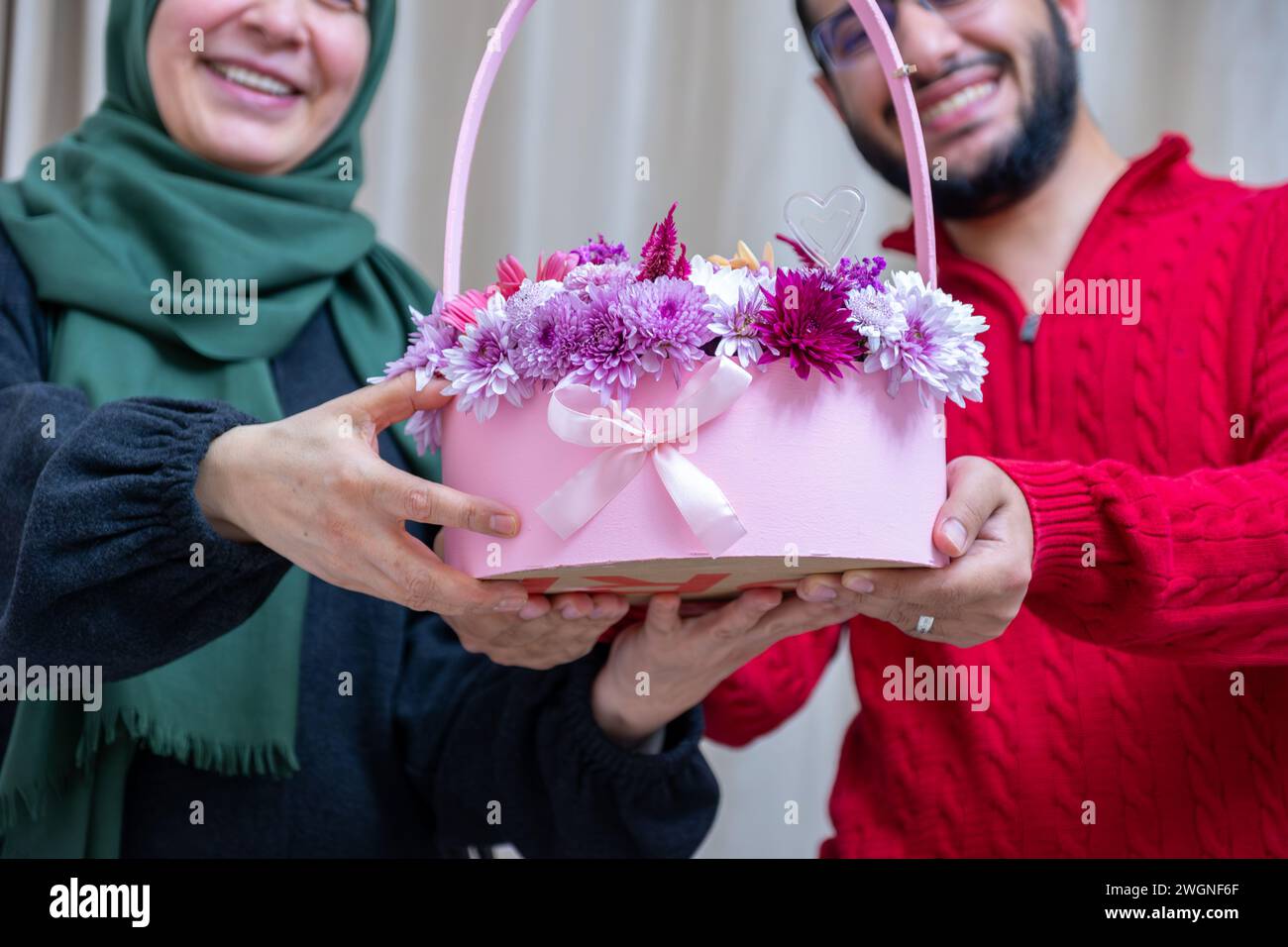 As a surprise in their home, a happy Muslim male gives roses to his ...