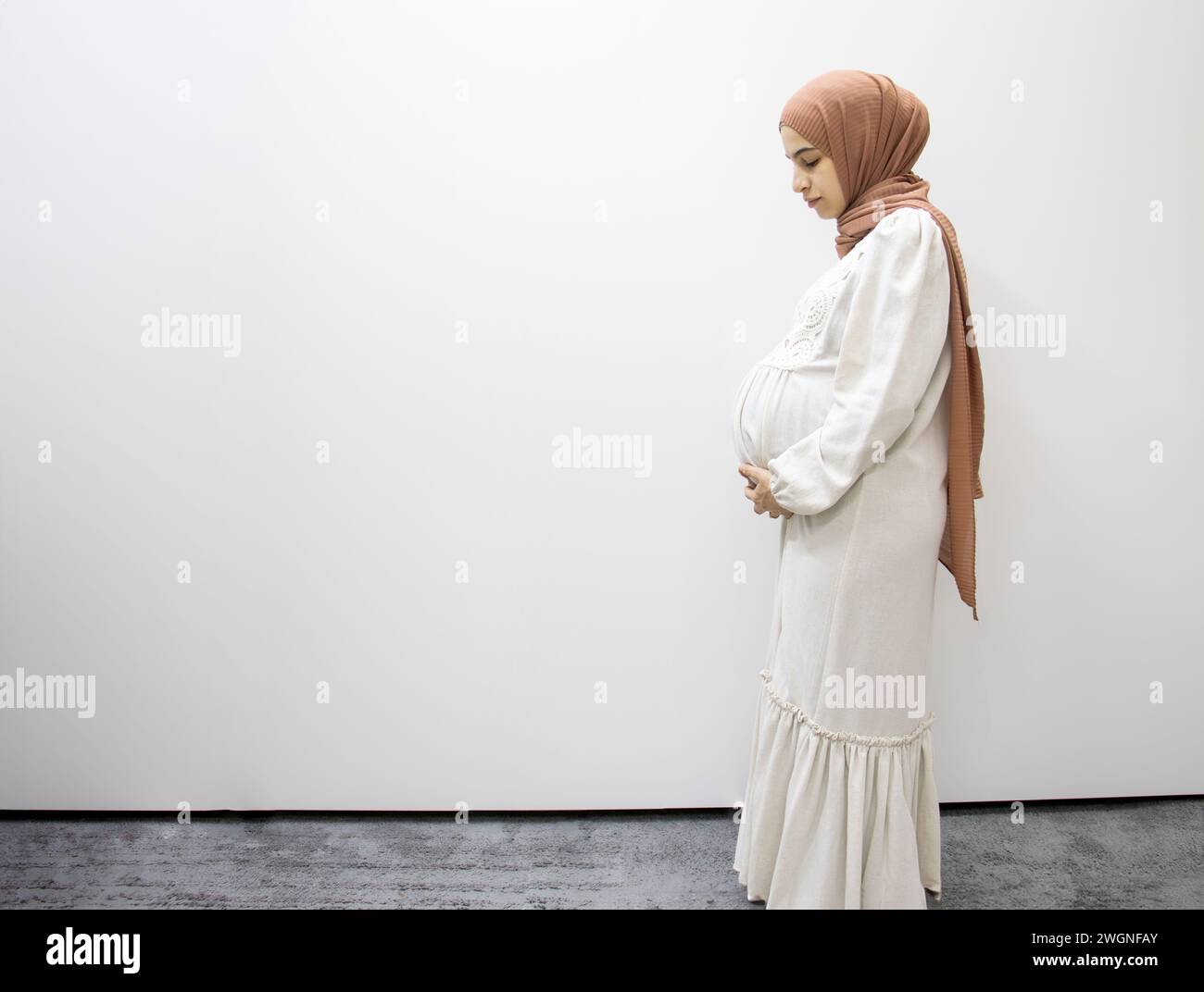 pregnant Arabic muslim female on isolated white background touching her ...