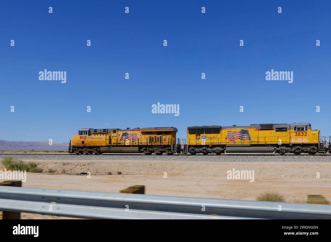 Two yellow freight trains with Union Pacific logos travel through a ...