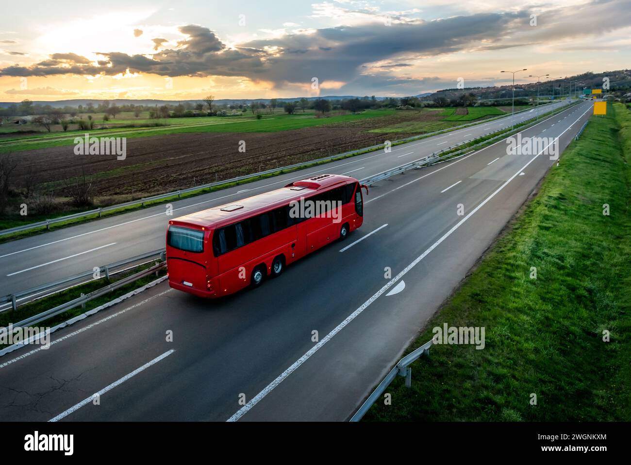Red Modern comfortable tourist bus driving through highway at bright ...