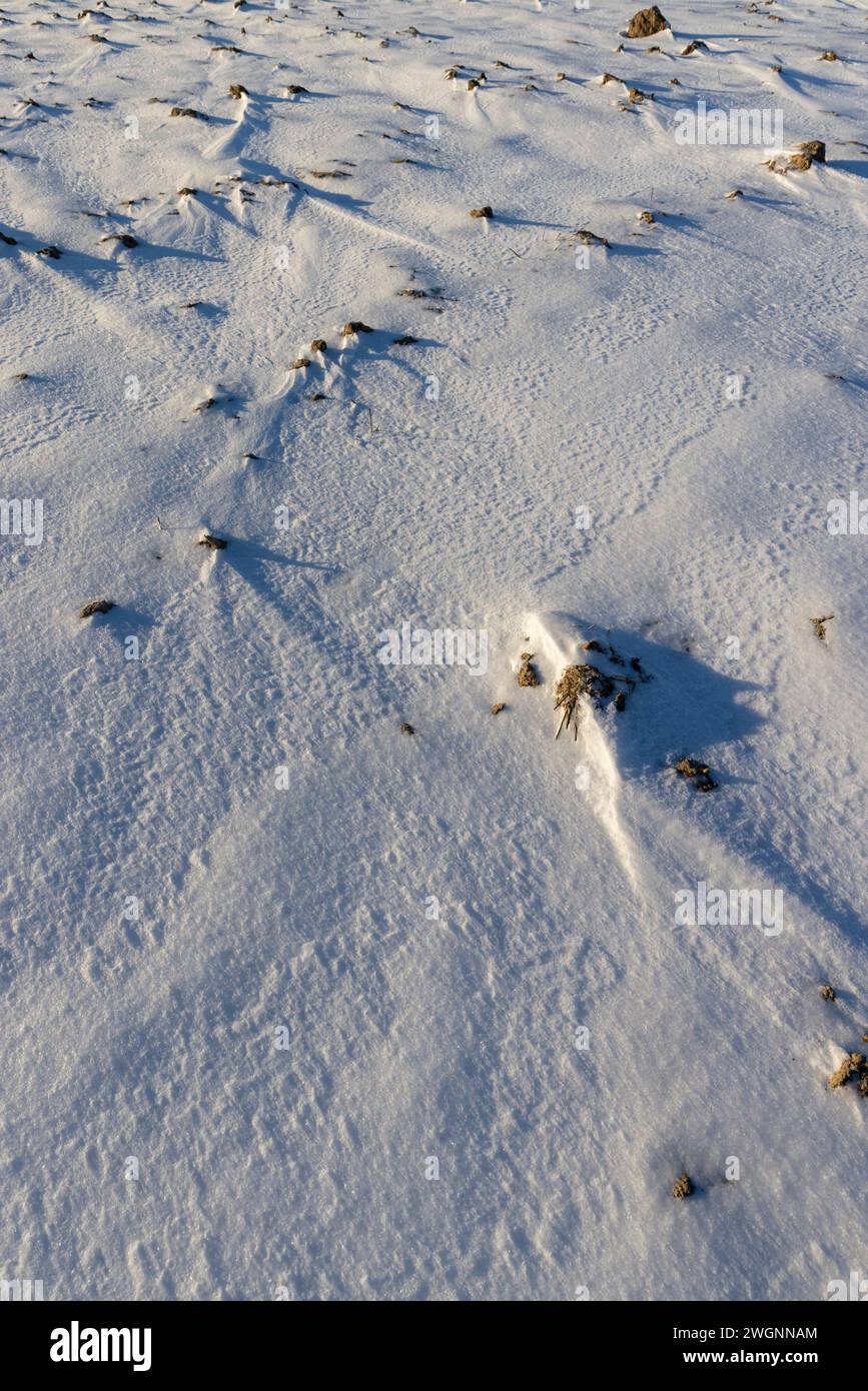 a field has been plowed with soil that is partially covered with snow ...