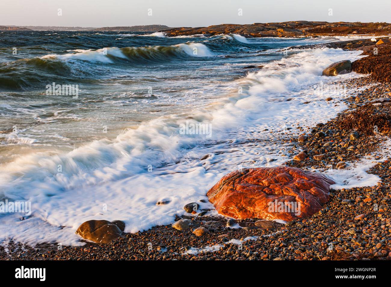 The dynamic scene captures the energy of waves hitting a pebbled beach ...