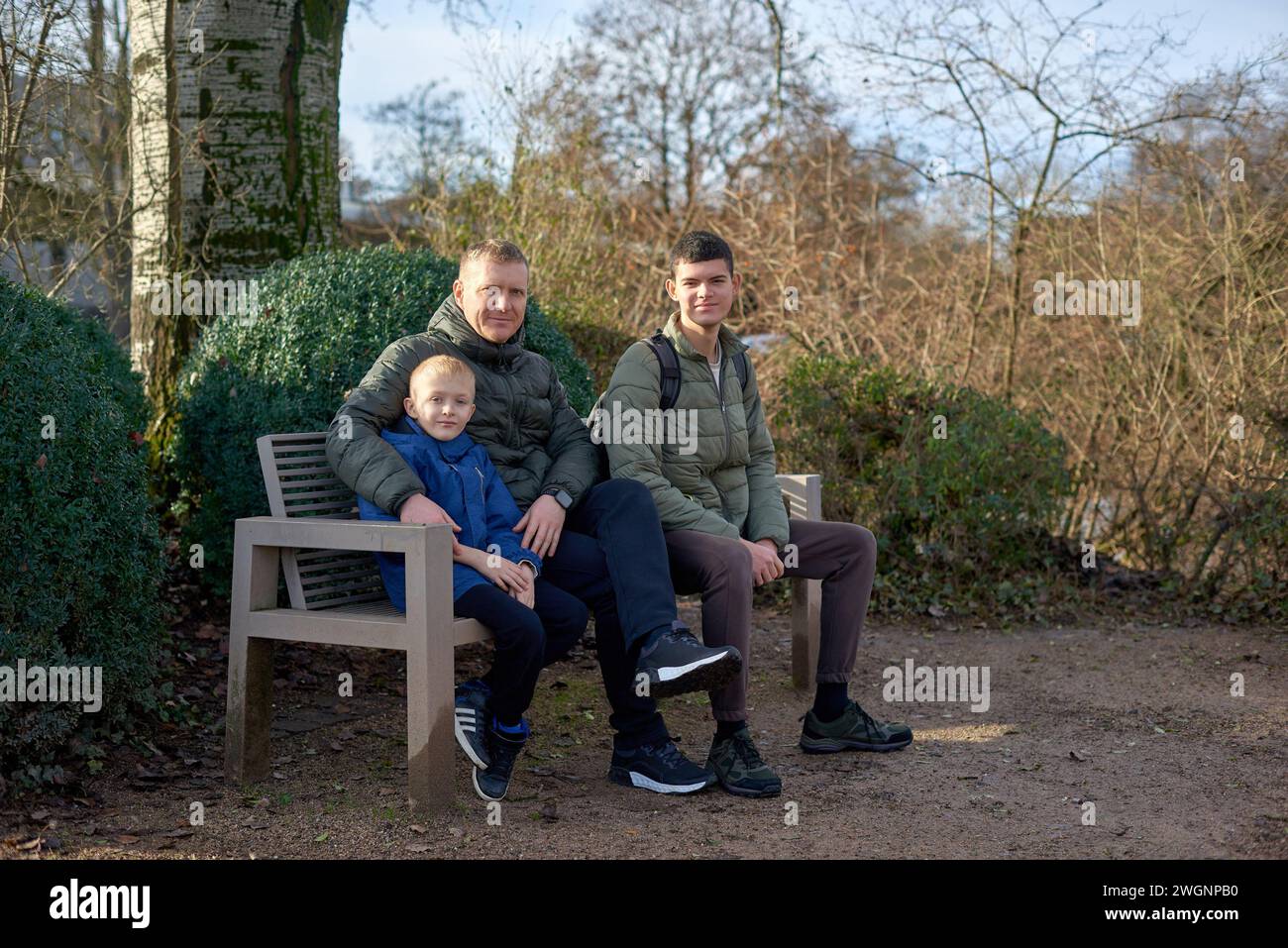 Dad with two sons sitting on a bench in autumn park. Autumnal Family ...