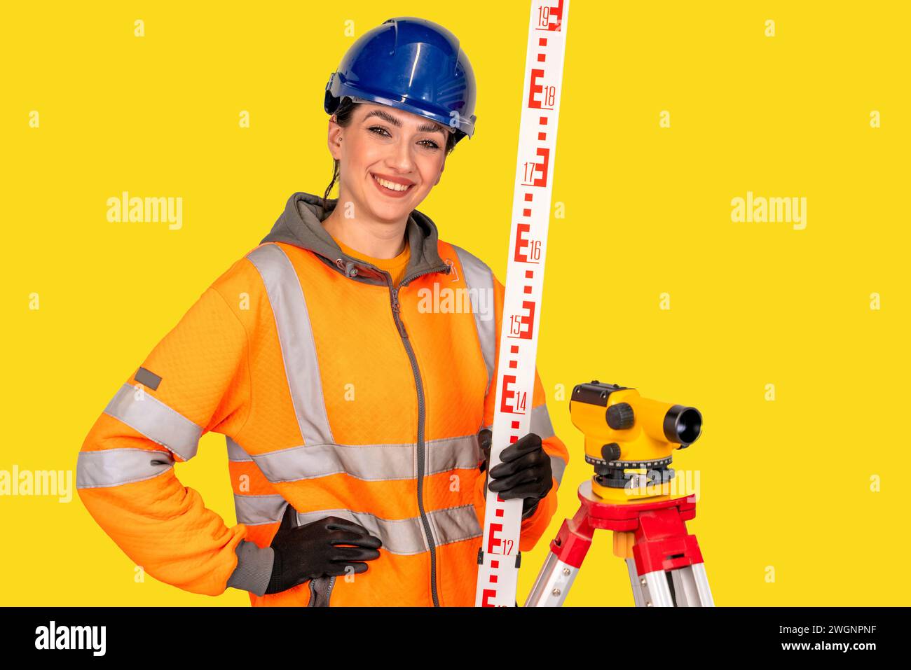 Smiling Woman in hard hat and protective clothes land surveyor working ...