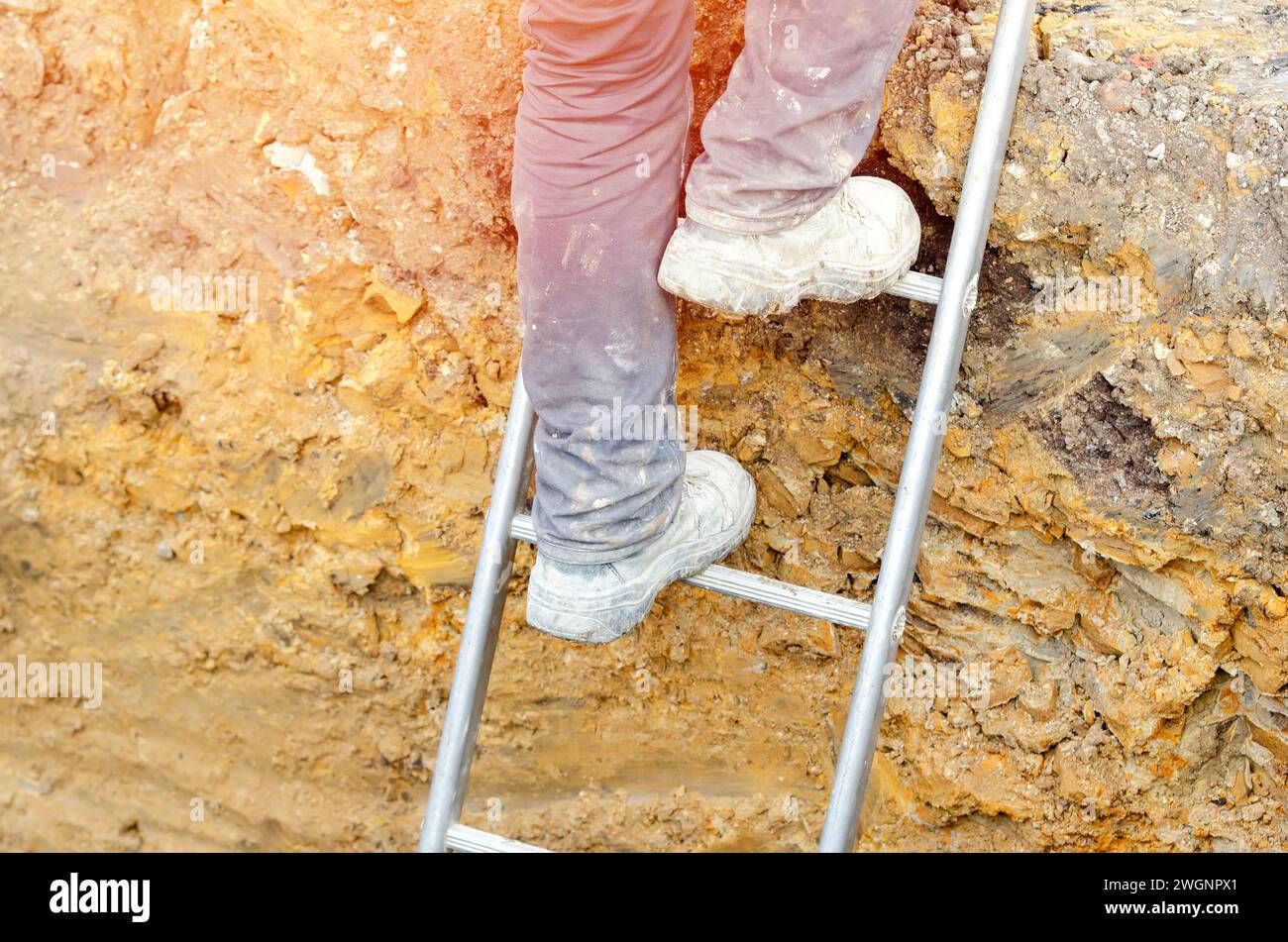 Builder going up the ladder to get out of trench Stock Photo - Alamy