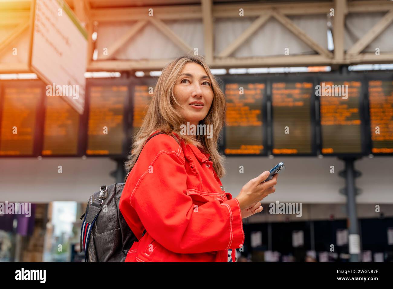 sad asian woman with backpack and holding smartphone while at the train ...