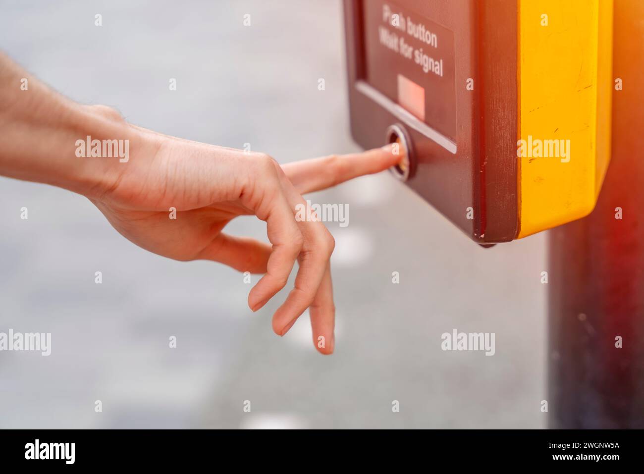 Hand of pedestrian pressing the traffic light control button to safely ...