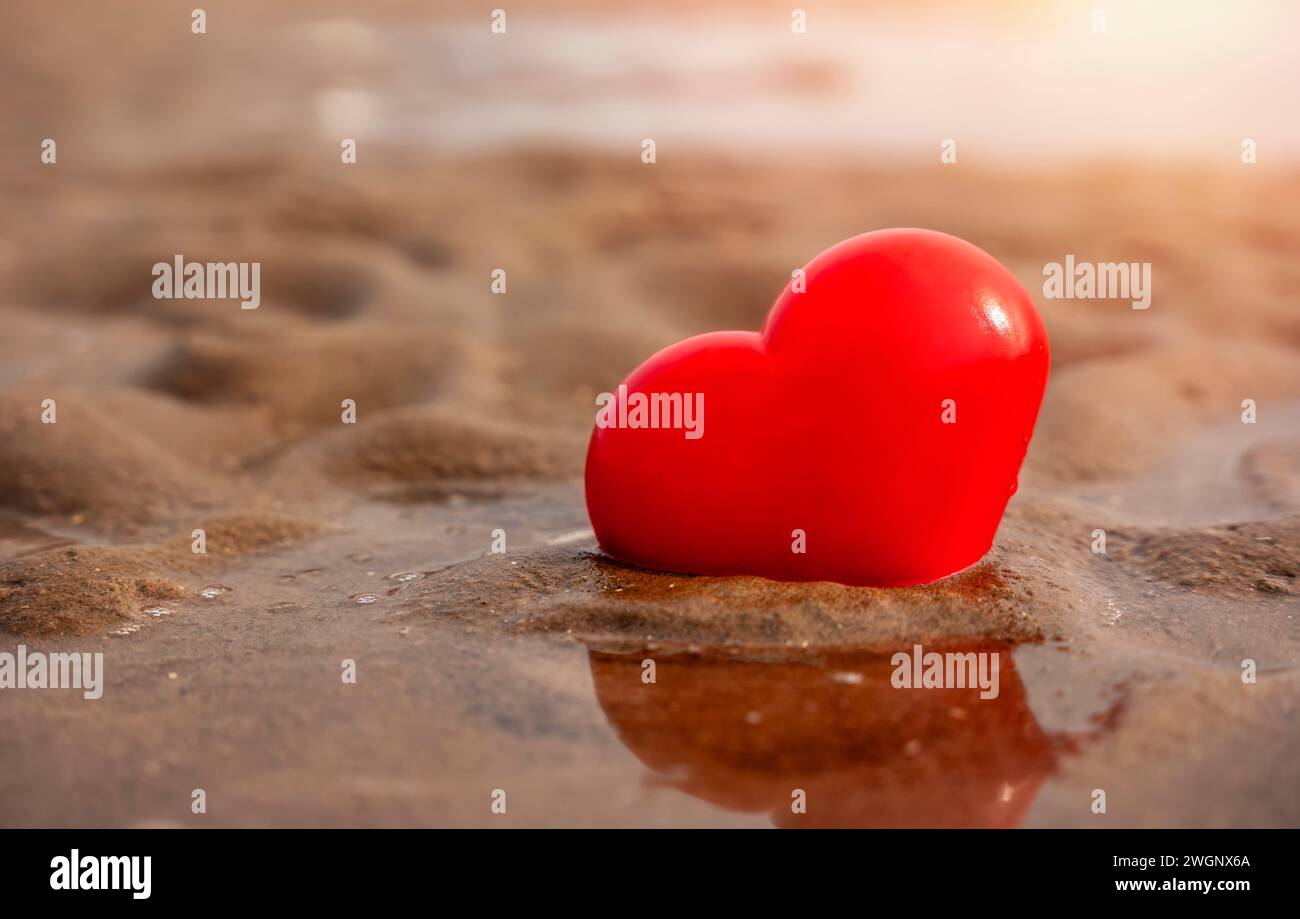 Big red heart in sand at coast. Fall in love with holiday at seaside ...