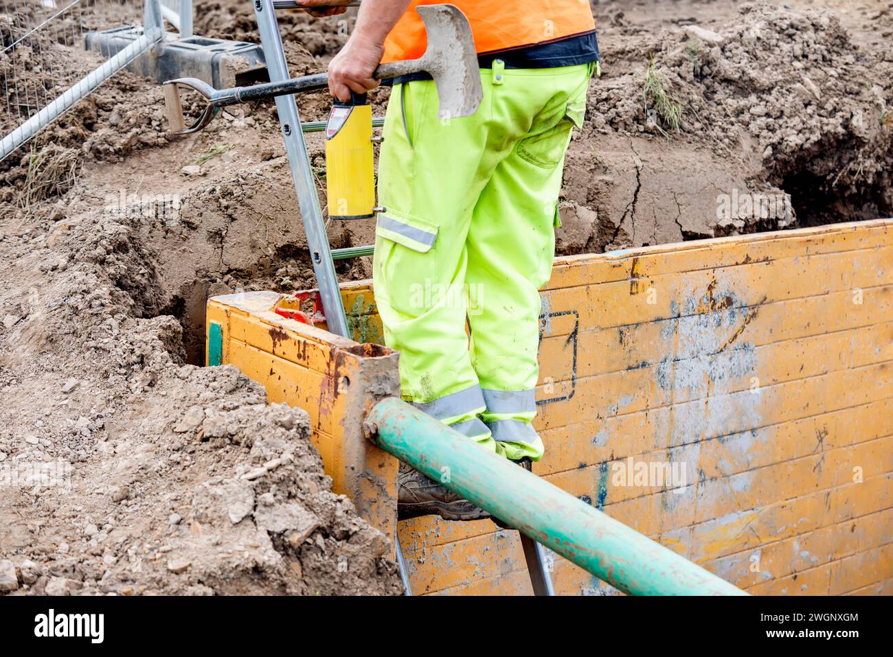 Groundworker builder using steps ladder to get out of the deep drainage ...