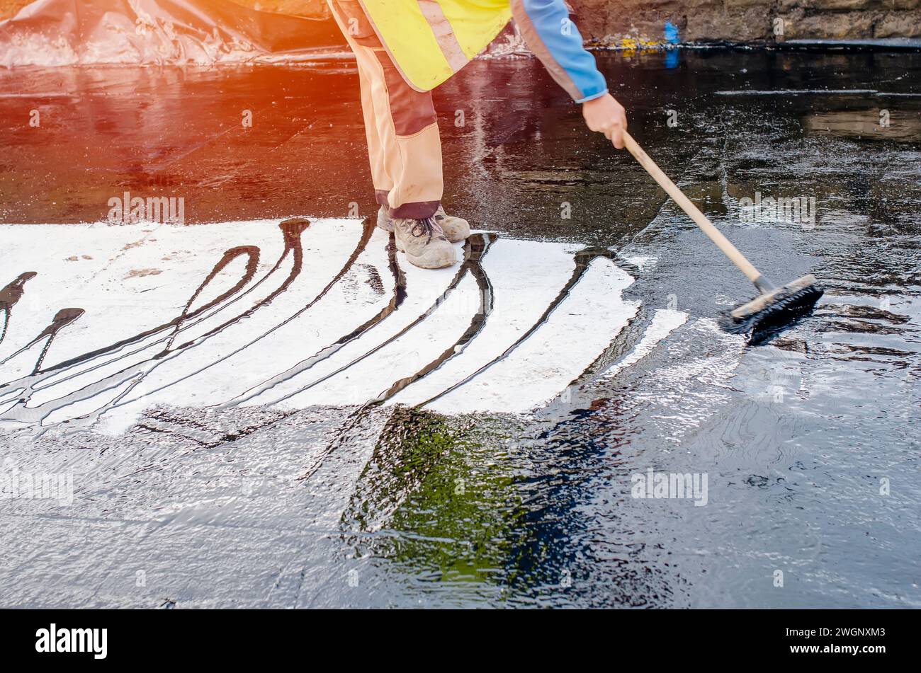 Waterproofing coating. Builder applying waterproofing bitumen mastic on ...