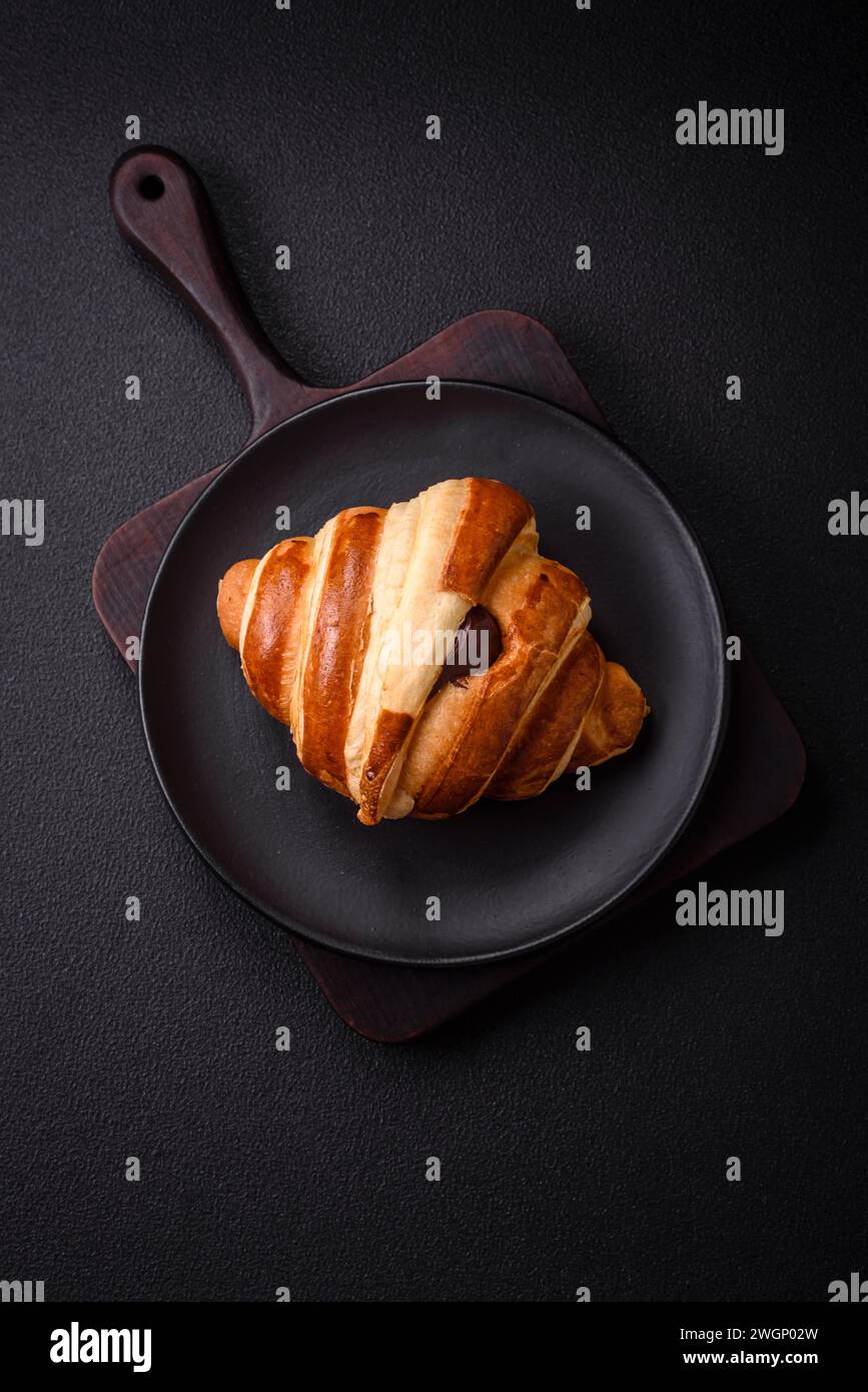 Delicious crispy sweet croissant cornet with chocolate on a dark ...
