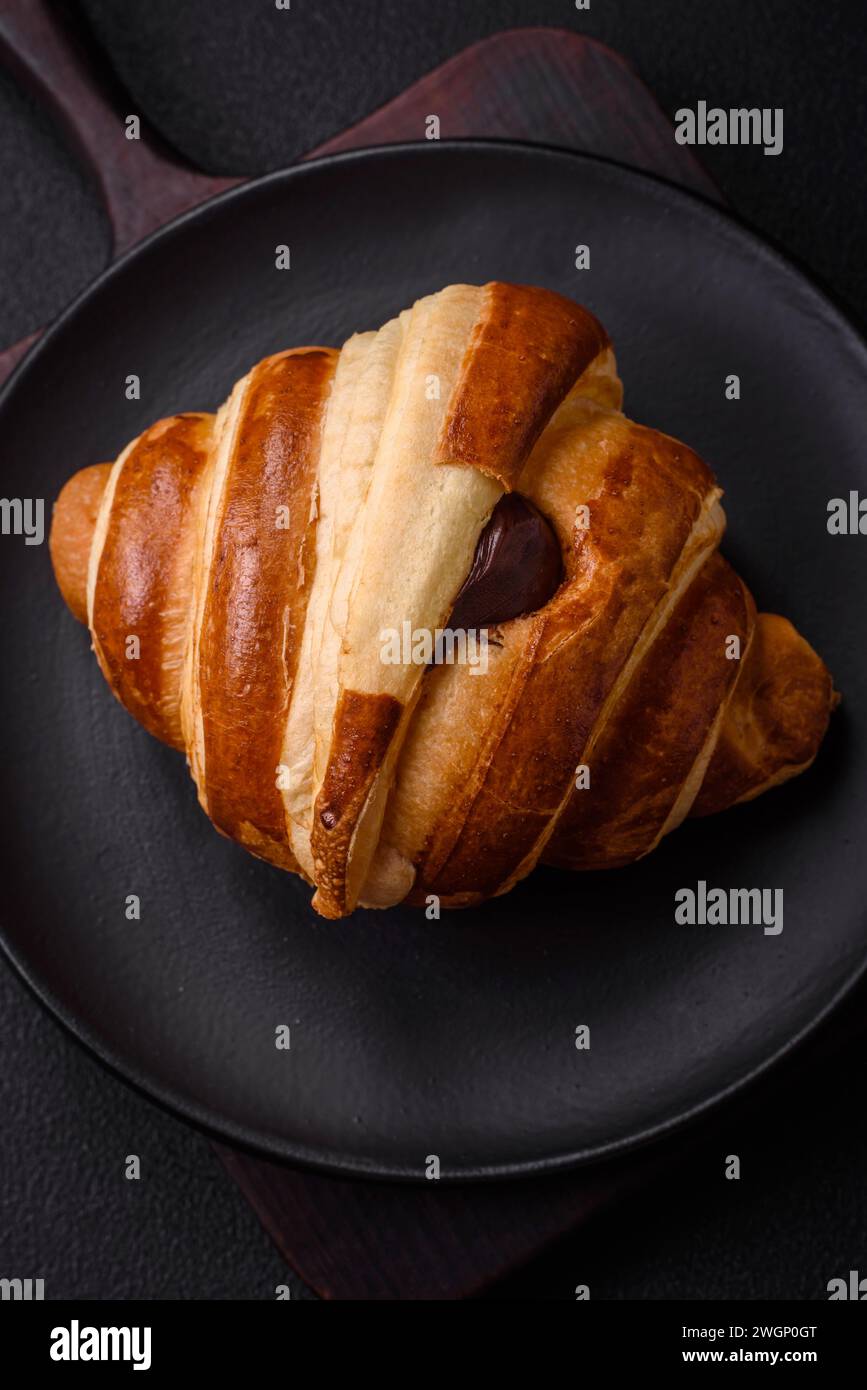 Delicious crispy sweet croissant cornet with chocolate on a dark ...