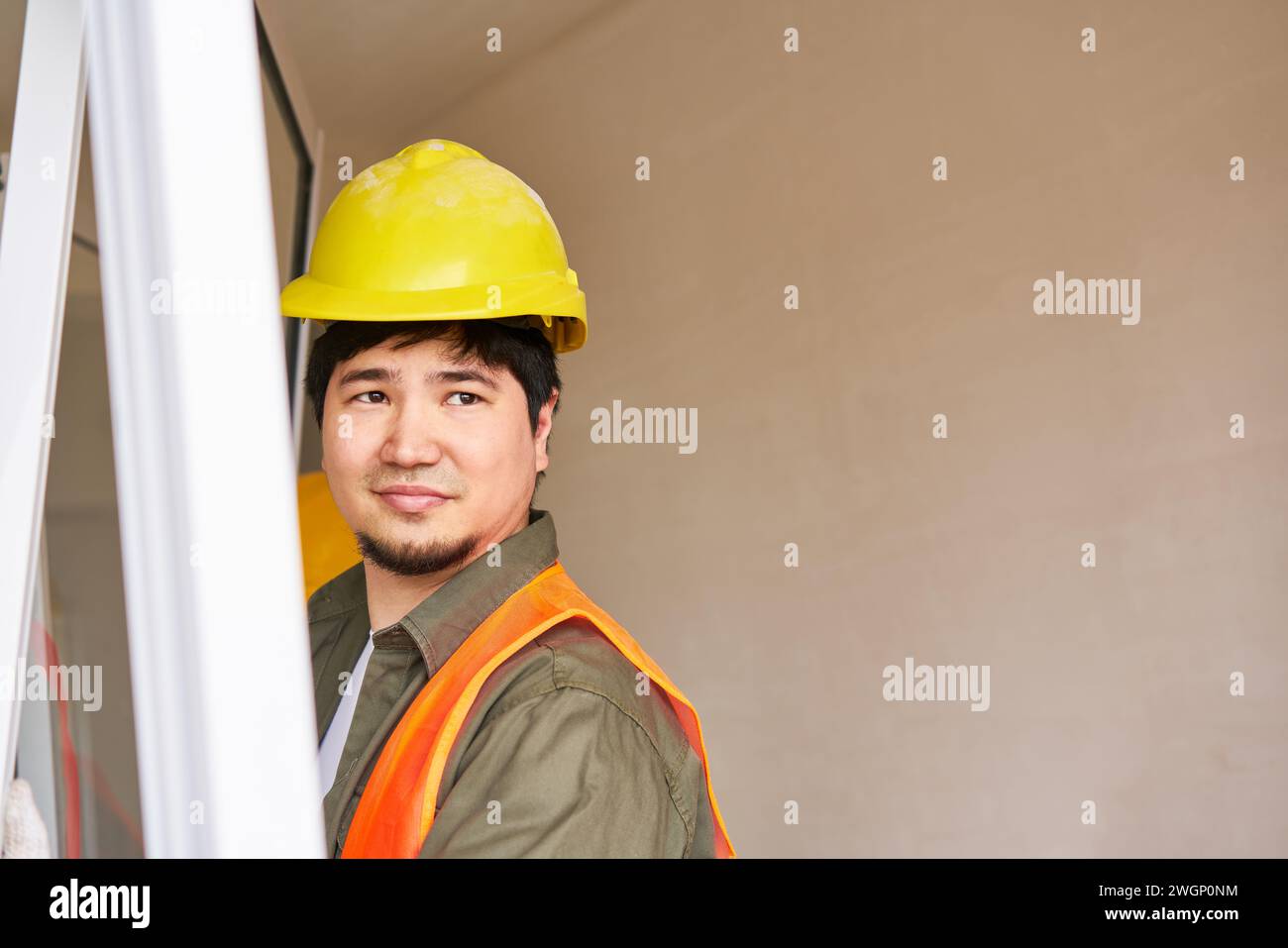 Young male construction worker carrying window frame Stock Photo - Alamy