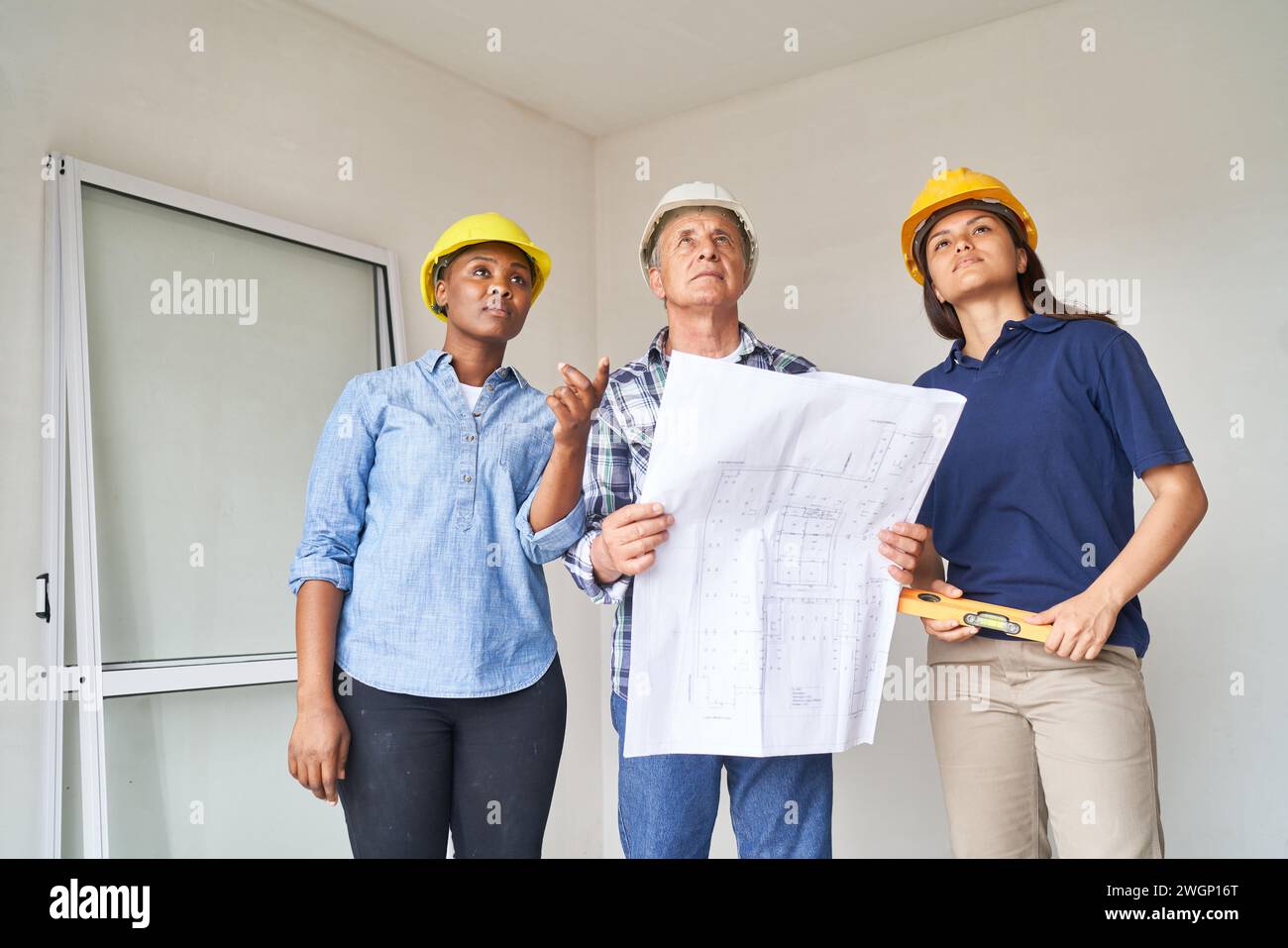 Diverse team group of female construction workers and architect with blueprint indoors onsite ...