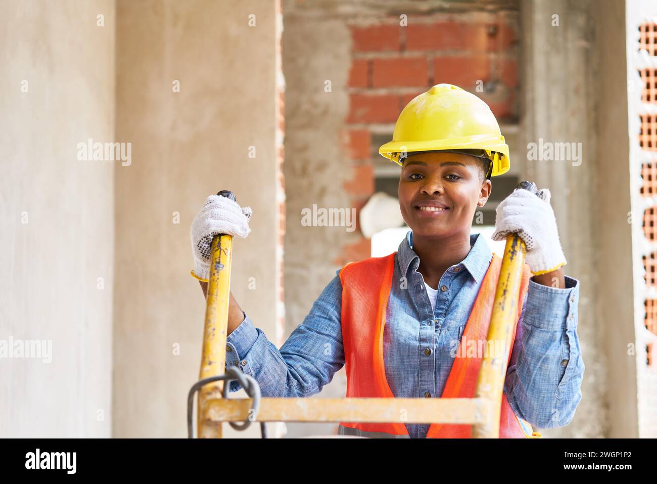 Smiling young female labor with cement mixer Stock Photo - Alamy