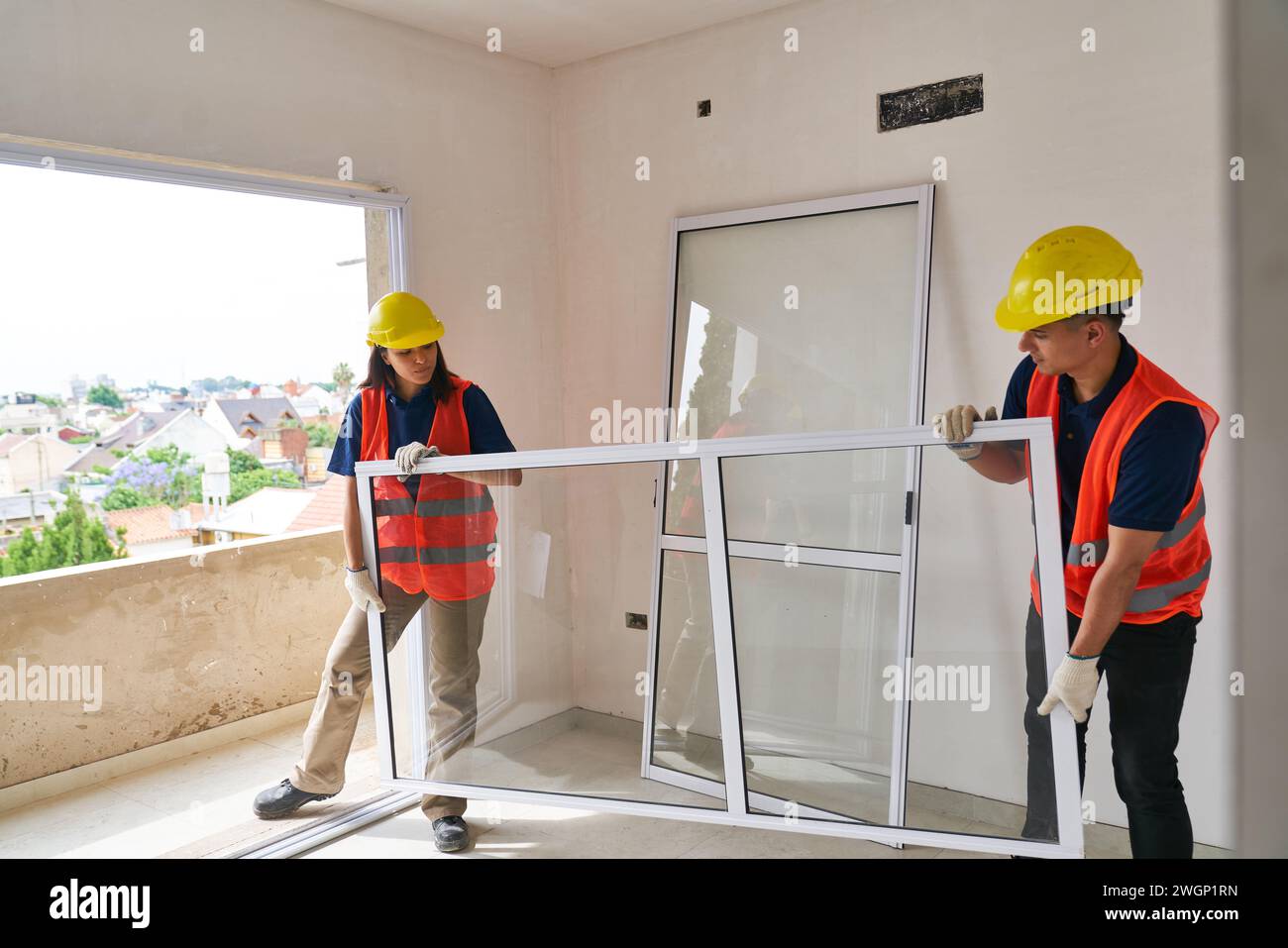 Full length of carpenters installing window in house Stock Photo - Alamy