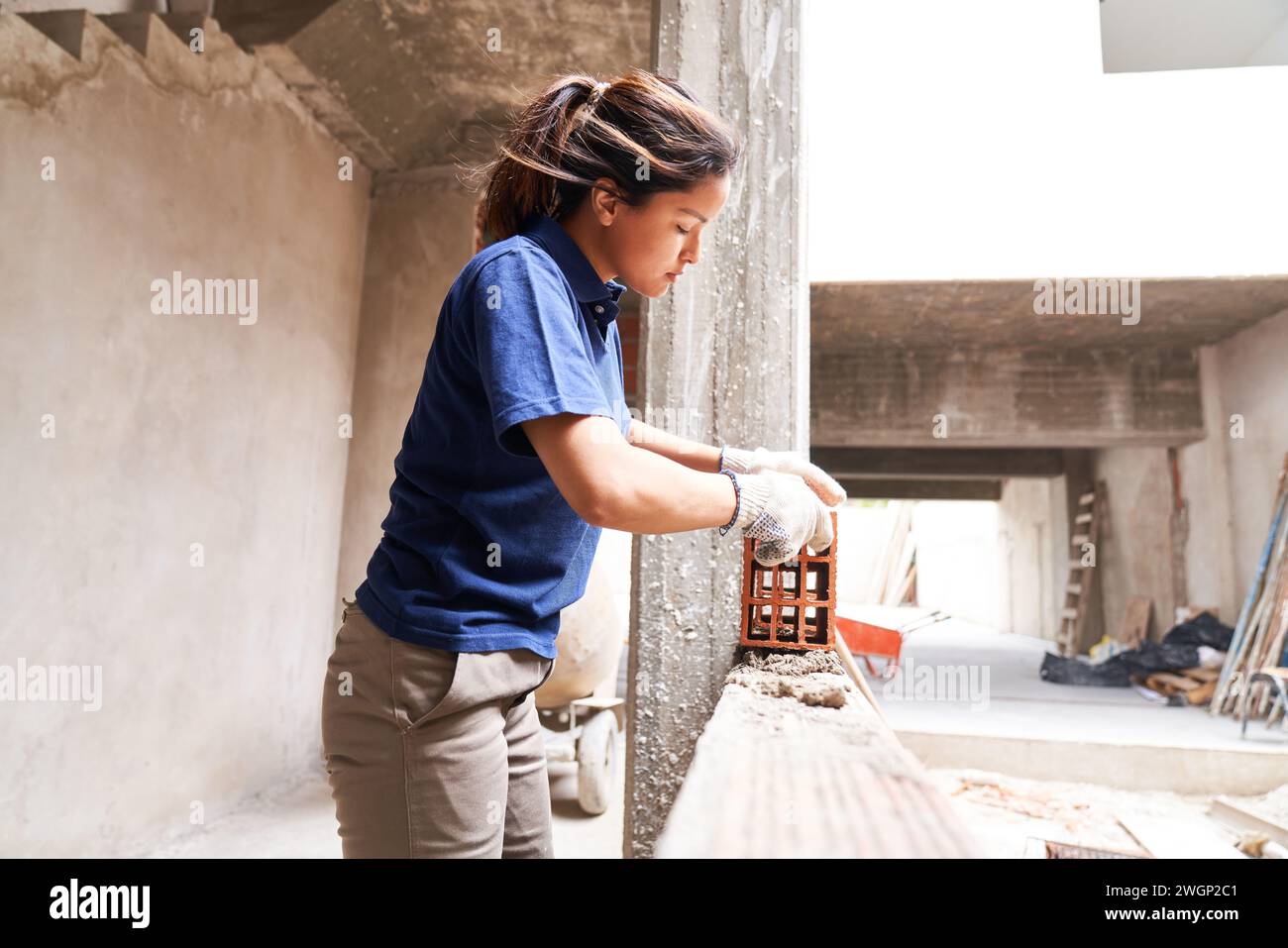 Female bricklayer positioning brick on cement Stock Photo - Alamy