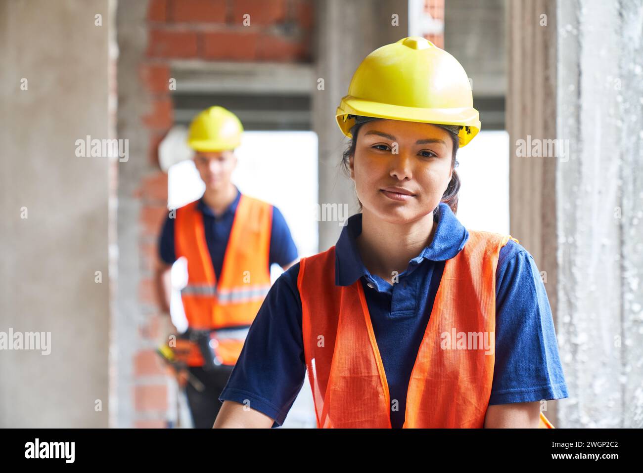 Confident female construction worker against coworker Stock Photo - Alamy