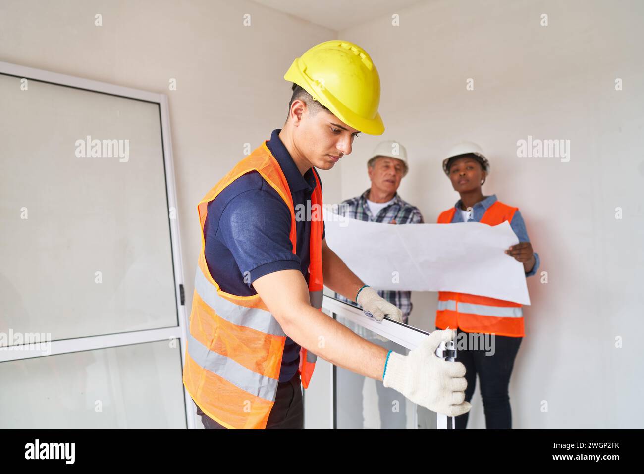 Carpenter examining window frame near coworkers Stock Photo - Alamy