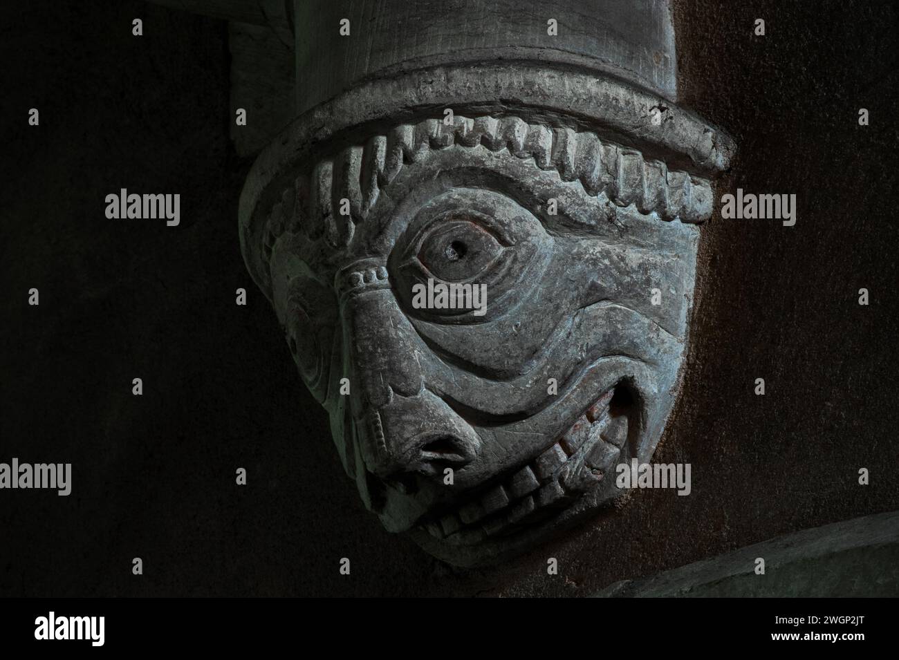 Staring eye above square and slab-like teeth. Grotesque face, sculpted ...
